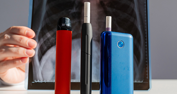 Doctor holds x-ray of lungs with e-cigarettes and vape in background ...
